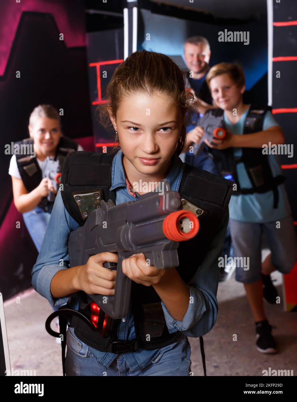 Smiling girl aiming laser gun at other players Stock Photo - Alamy