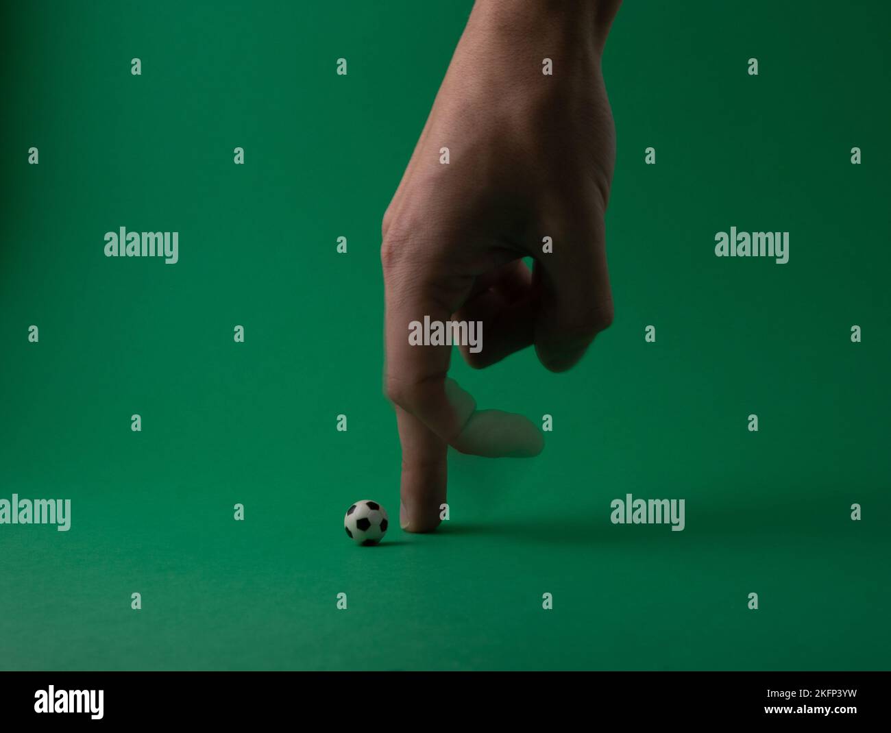 fingers of the hand kicking a small black and white toy soccer ball on ...