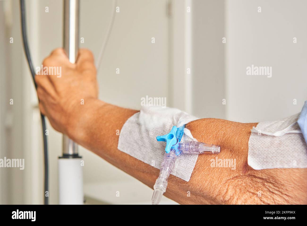 detail of arm of senior lady with intravenous line holding drip foot in ...