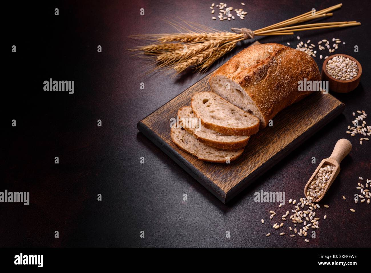 A loaf of brown bread with grains of cereals on a wooden cutting board ...