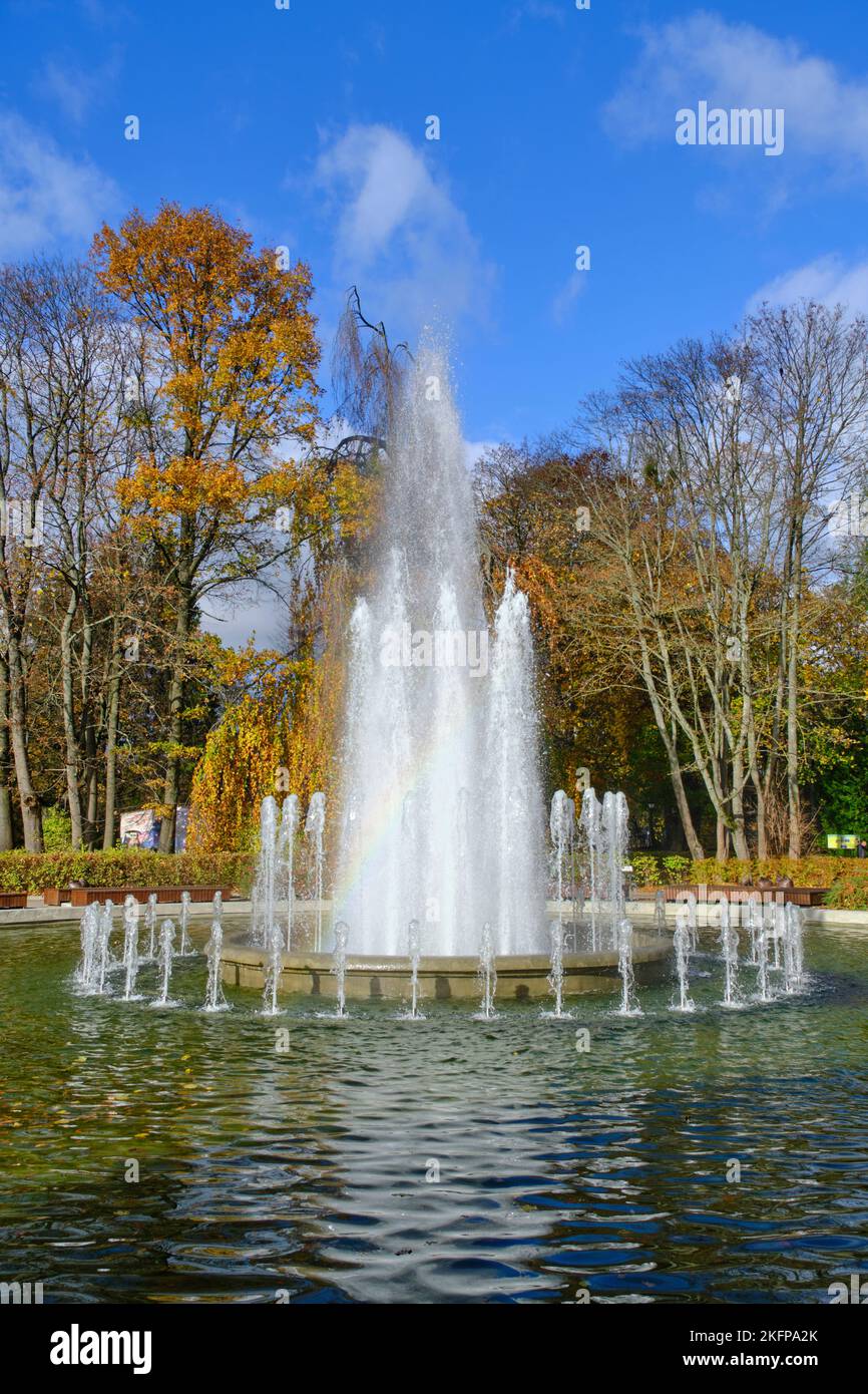 Beautiful fountain with blue sky and trees with yellowed autumn foliage ...