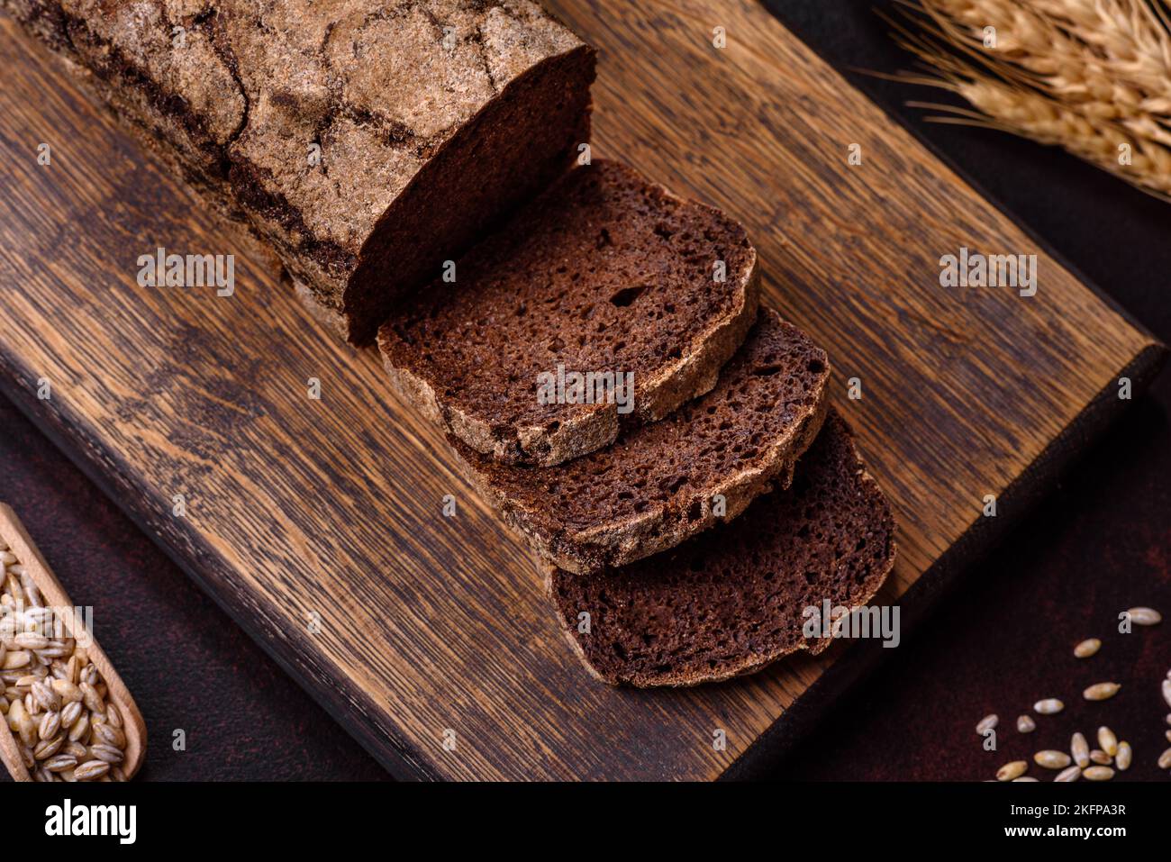 A loaf of brown bread with grains of cereals on a wooden cutting board ...