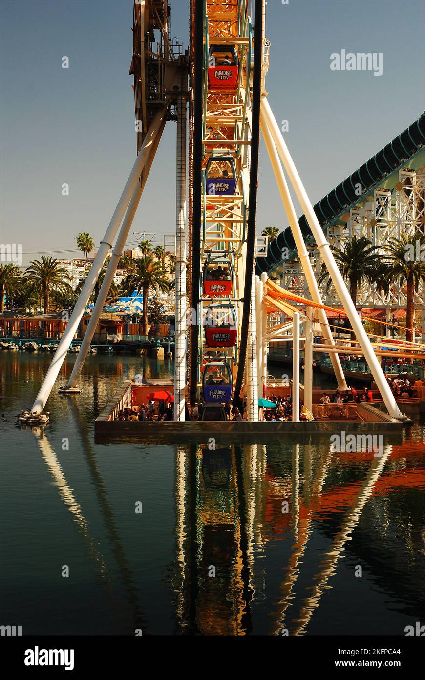 A large Ferris wheel spins over a lake, creating a reflection in the ...
