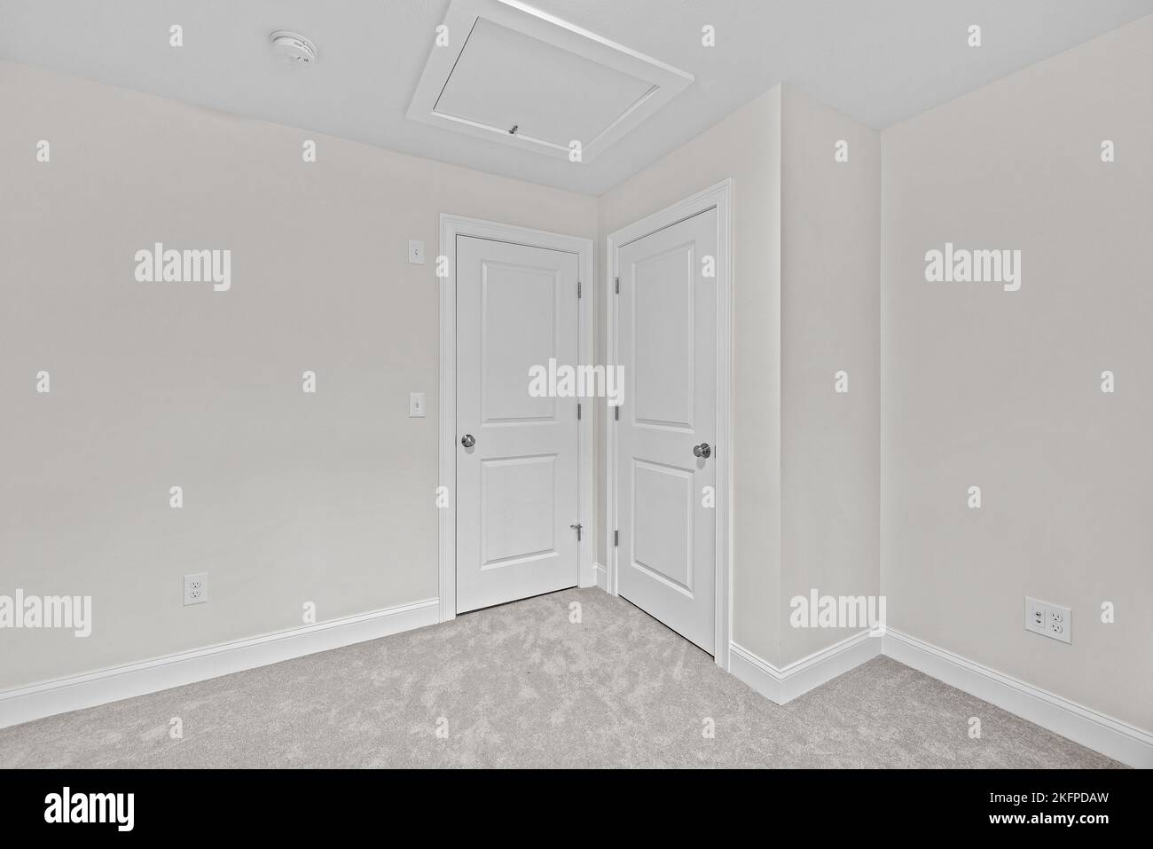 A minimalistic white room with two doors on either side of the corner ...