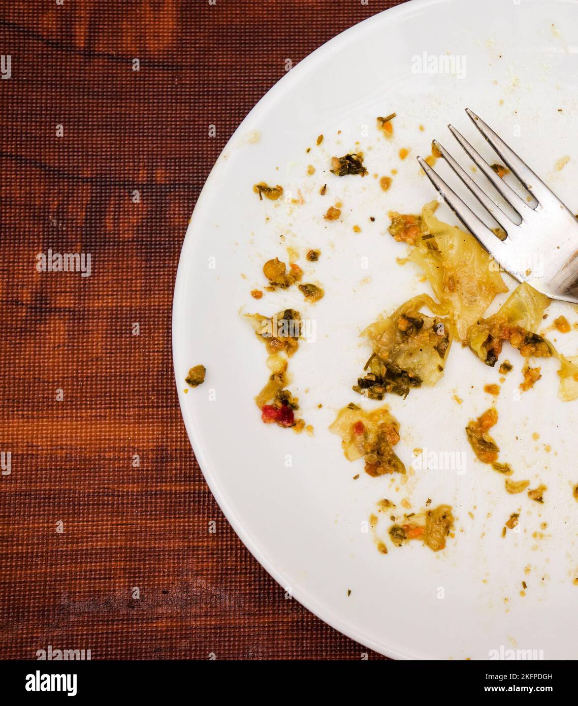 white plate , and fork with leftover food on the table after dinner ...