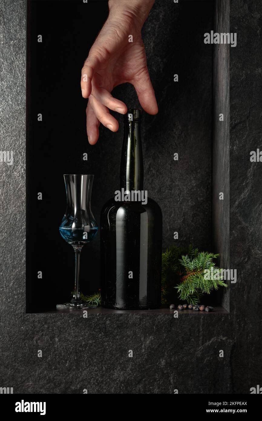 Hand reach for a vintage bottle of gin. A concept image on the theme of ...