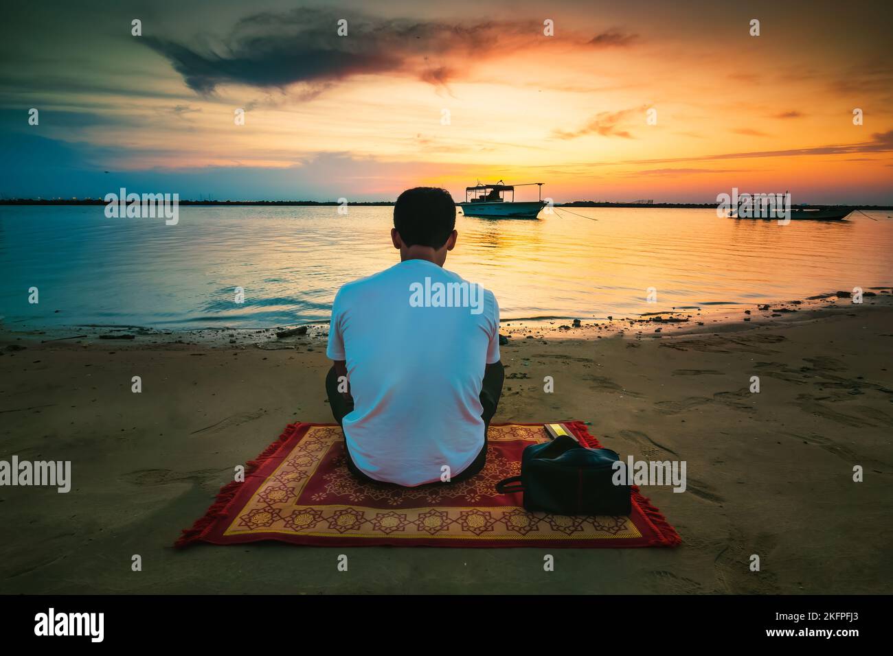 Man sitting and watching sunset over the sea. Dammam, Saudi Arabia ...