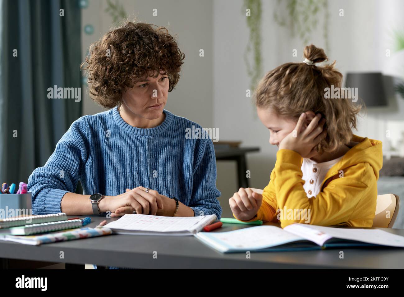 Young teacher teaching difficult child at home, they sitting together ...