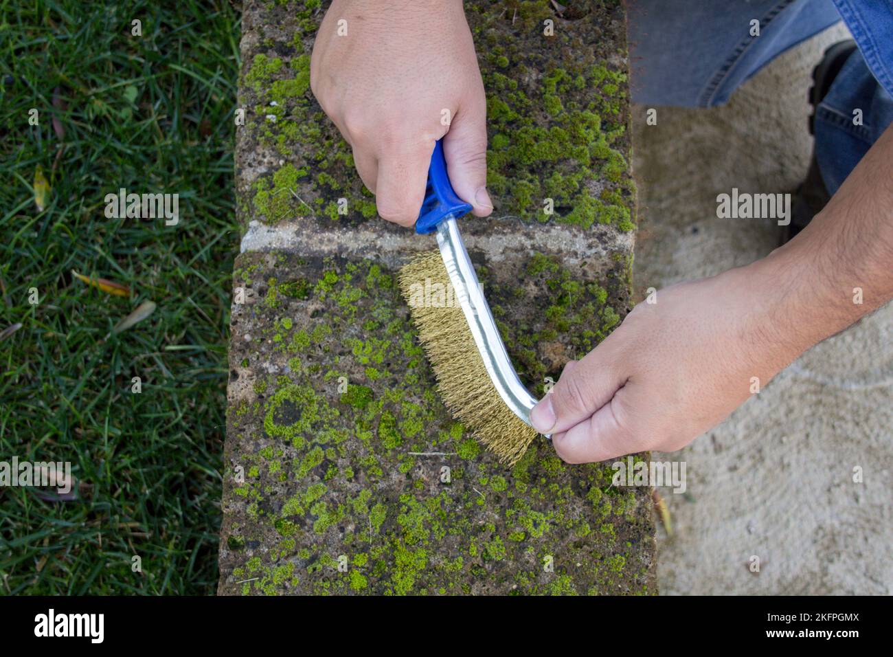 Image of the hands of a handyman who with a steel brush cleans the tuff ...