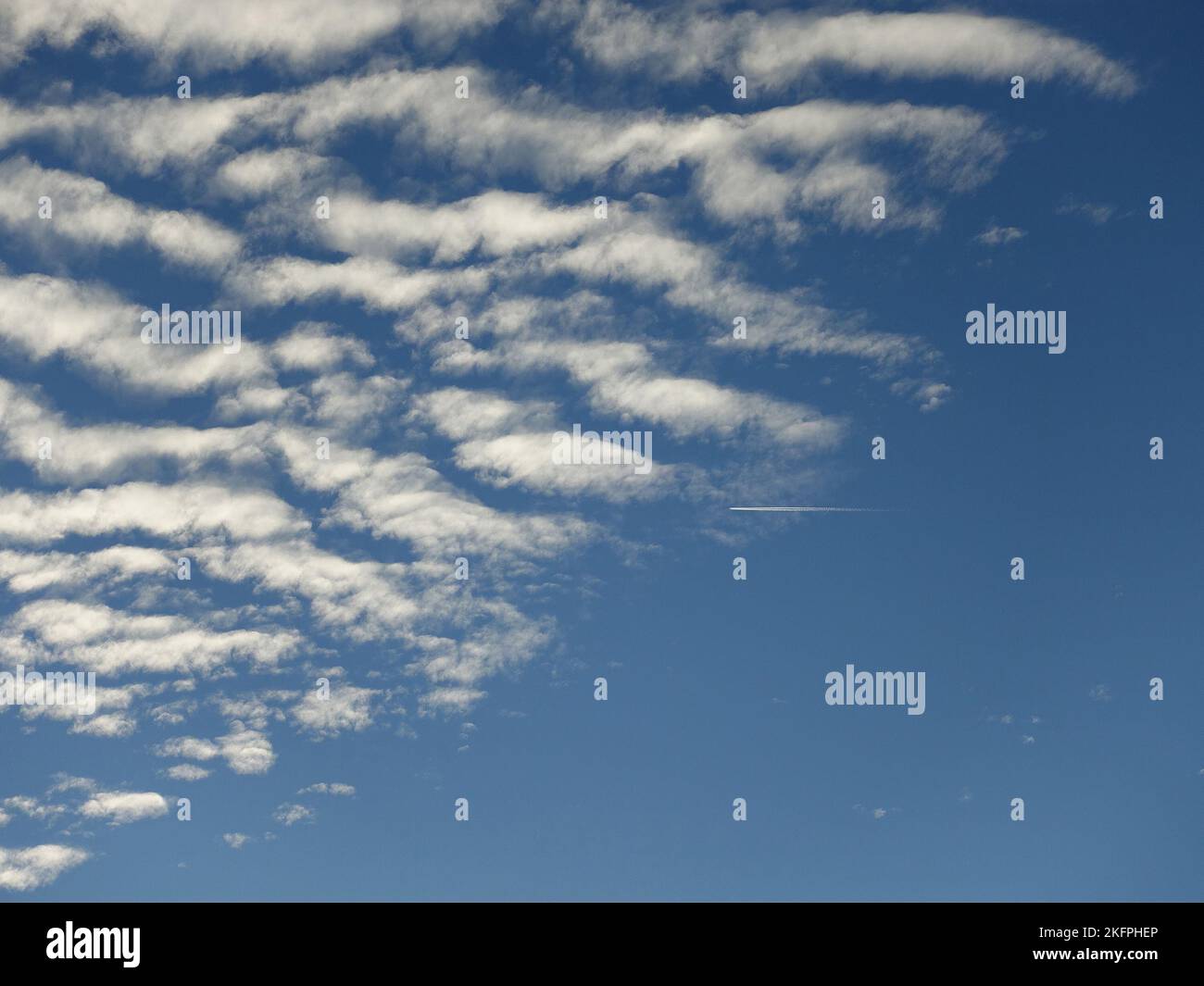 Airplane trail on the blue sky with interesting clouds Stock Photo - Alamy