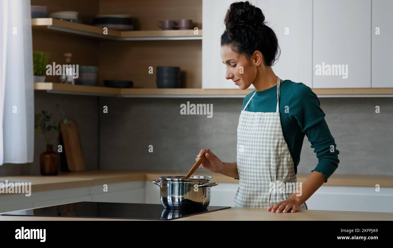 Female chef arabian woman cooker wife mother cooking aromatic dish on stove at home kitchen ...