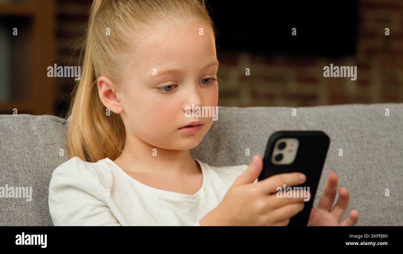 Adorable little kid girl cute child sitting on cozy couch alone in ...
