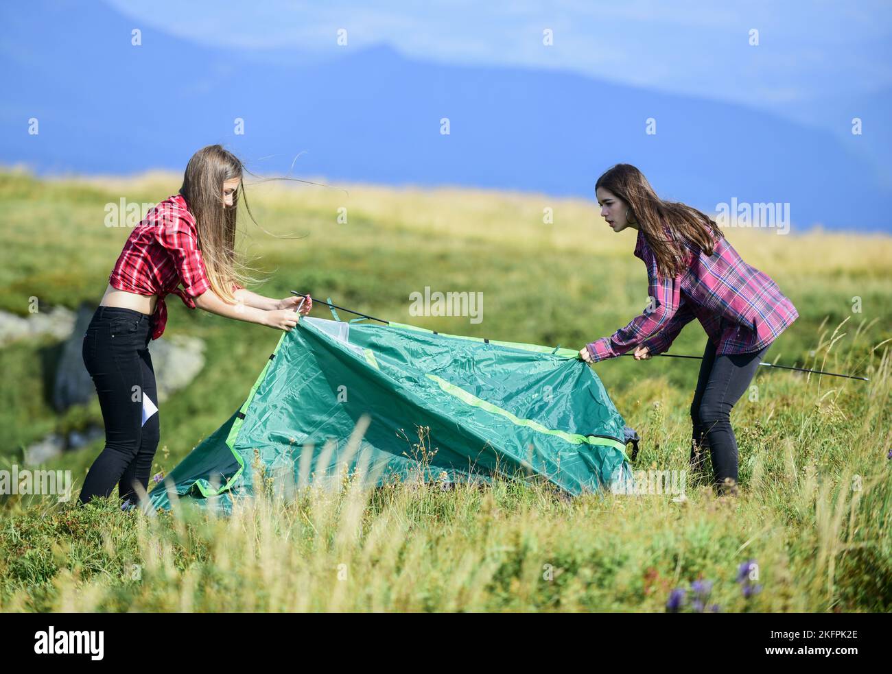 Camping and hiking. In middle of nowhere. Girls set up tent on top of ...