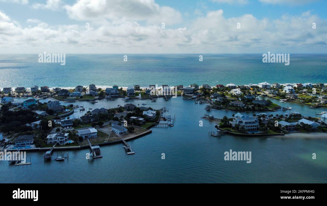 A wide view of a waterfront with houses on the docks and blue skies ...