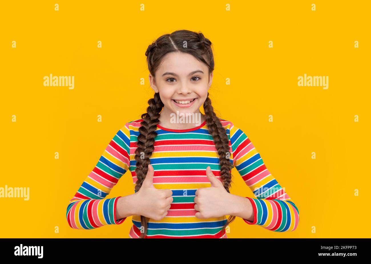 teen braided girl in childhood isolated on yellow background, thumb up ...