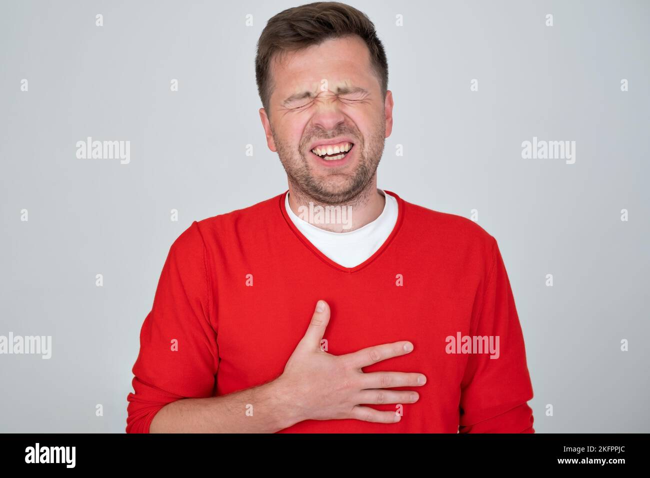 Caucasian man using his hand and pressing on stomach on grey background ...