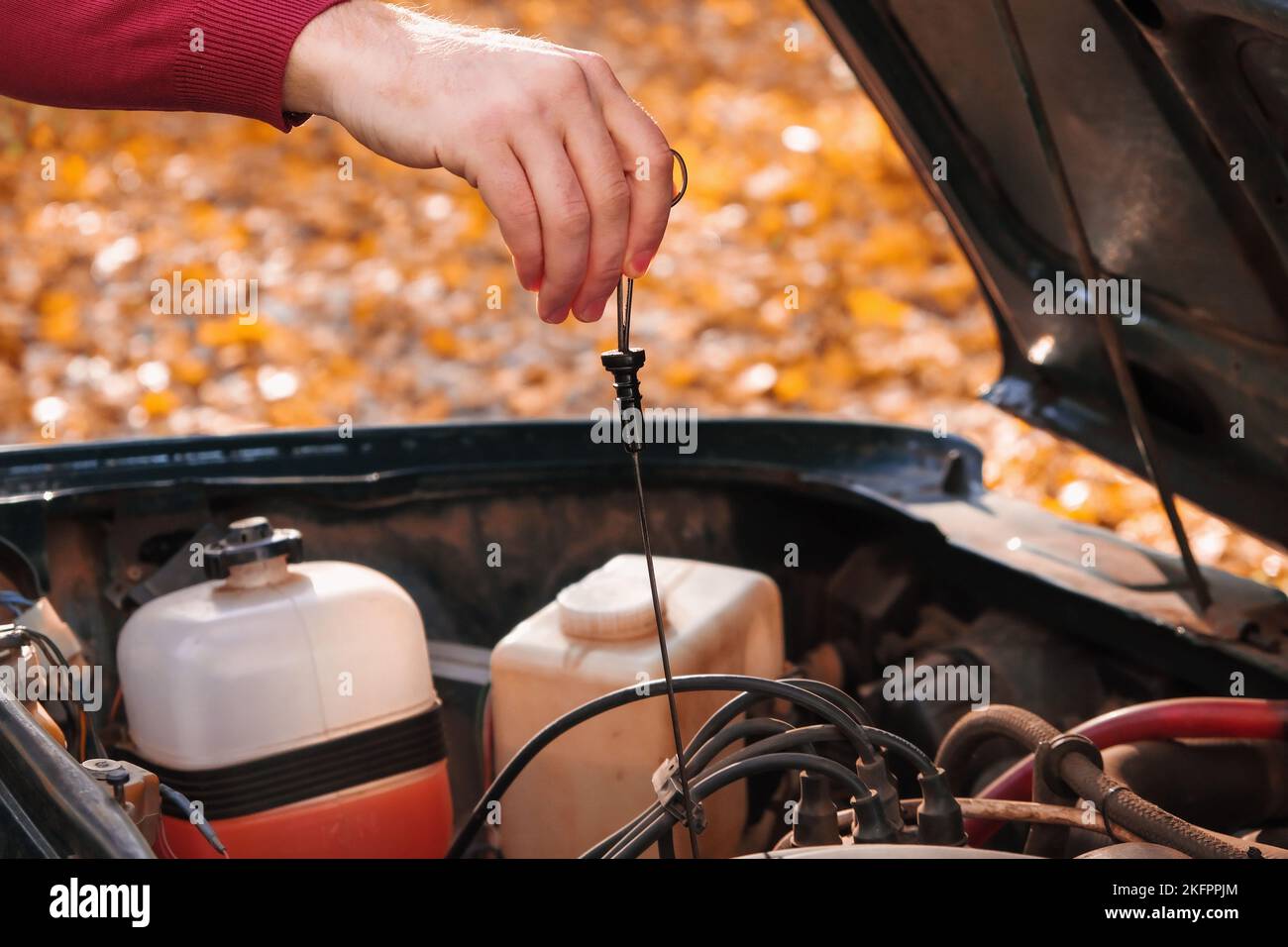 A man checks the oil level in the car engine. Self-service of the car ...