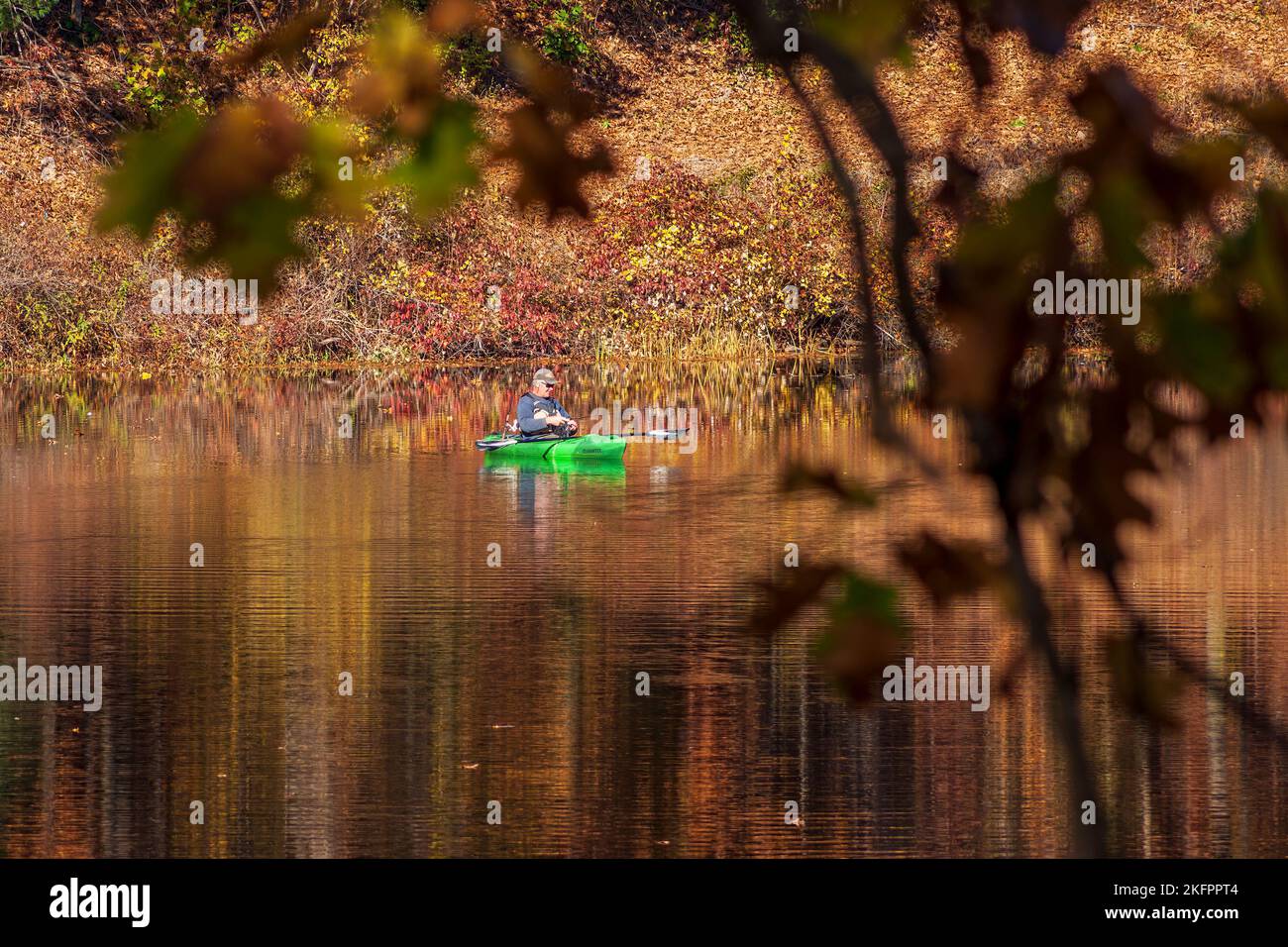 Kayak fishing on Charles River. Fisherman reeling the line. Forest and ...