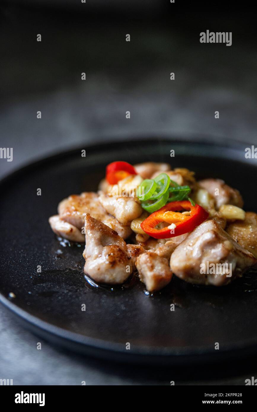 A vertical close-up shot of fried chicken served with colorful peppers ...