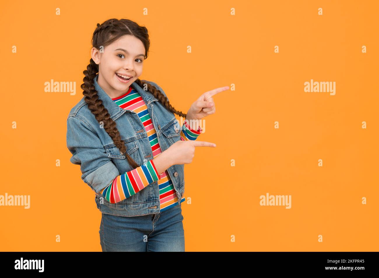 Excited little girl with braids wear denim clothes, promoting goods ...