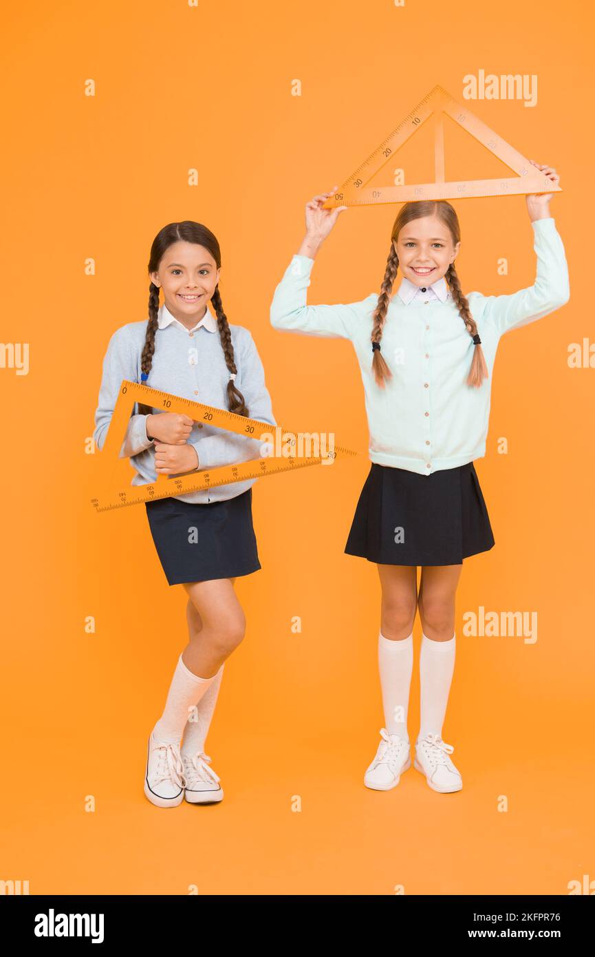 Measuring angles at geometry. Cute schoolgirls holding triangles for ...