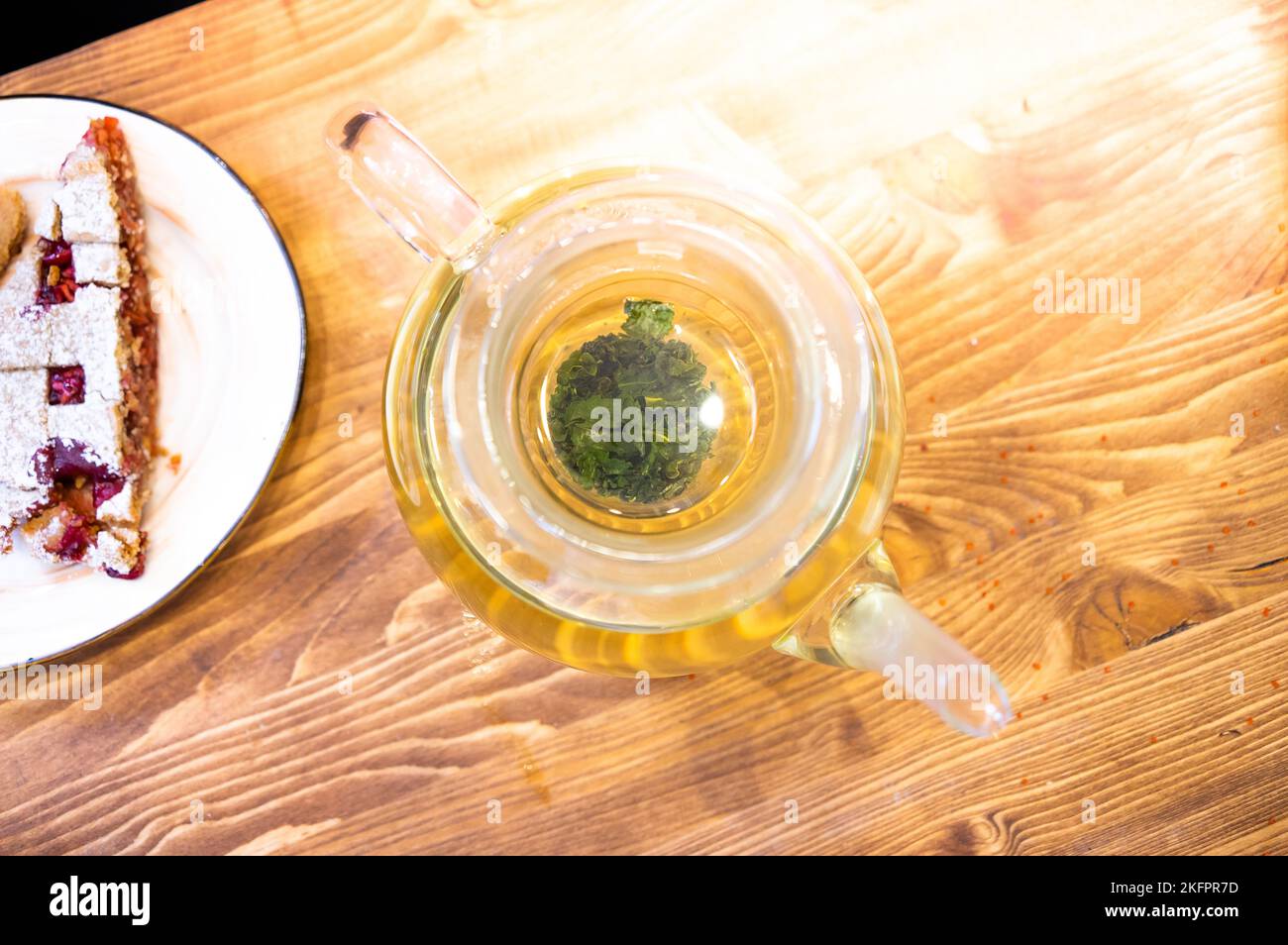 green tea in a glass teapot on wooden background with apiece of apple ...