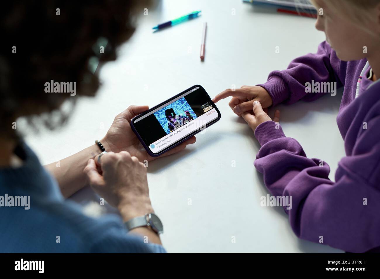 Close-up of mother using her smartphone and showing video to her ...