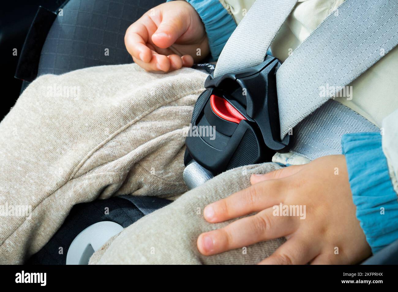 Little baby child fastened with security belt in safety car seat, close ...