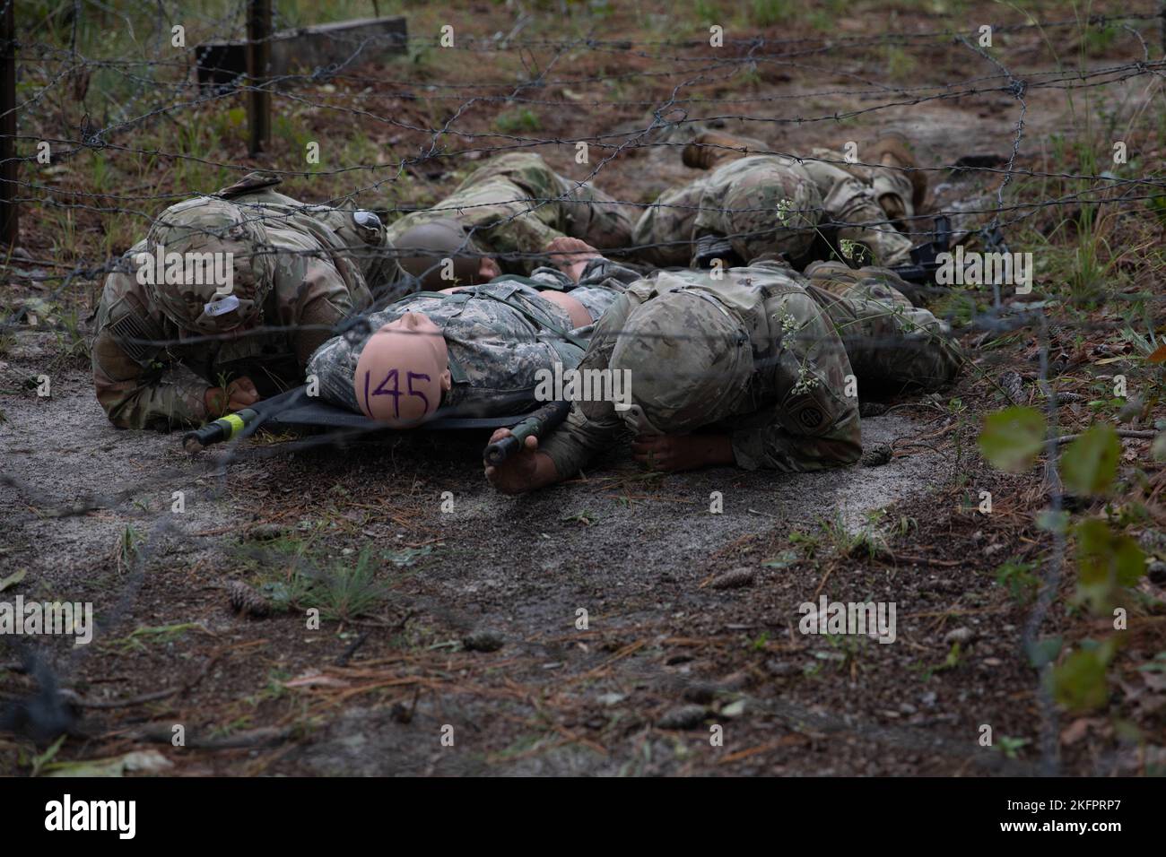 Competitors representing U.S. Army Medical Command low crawl with a ...