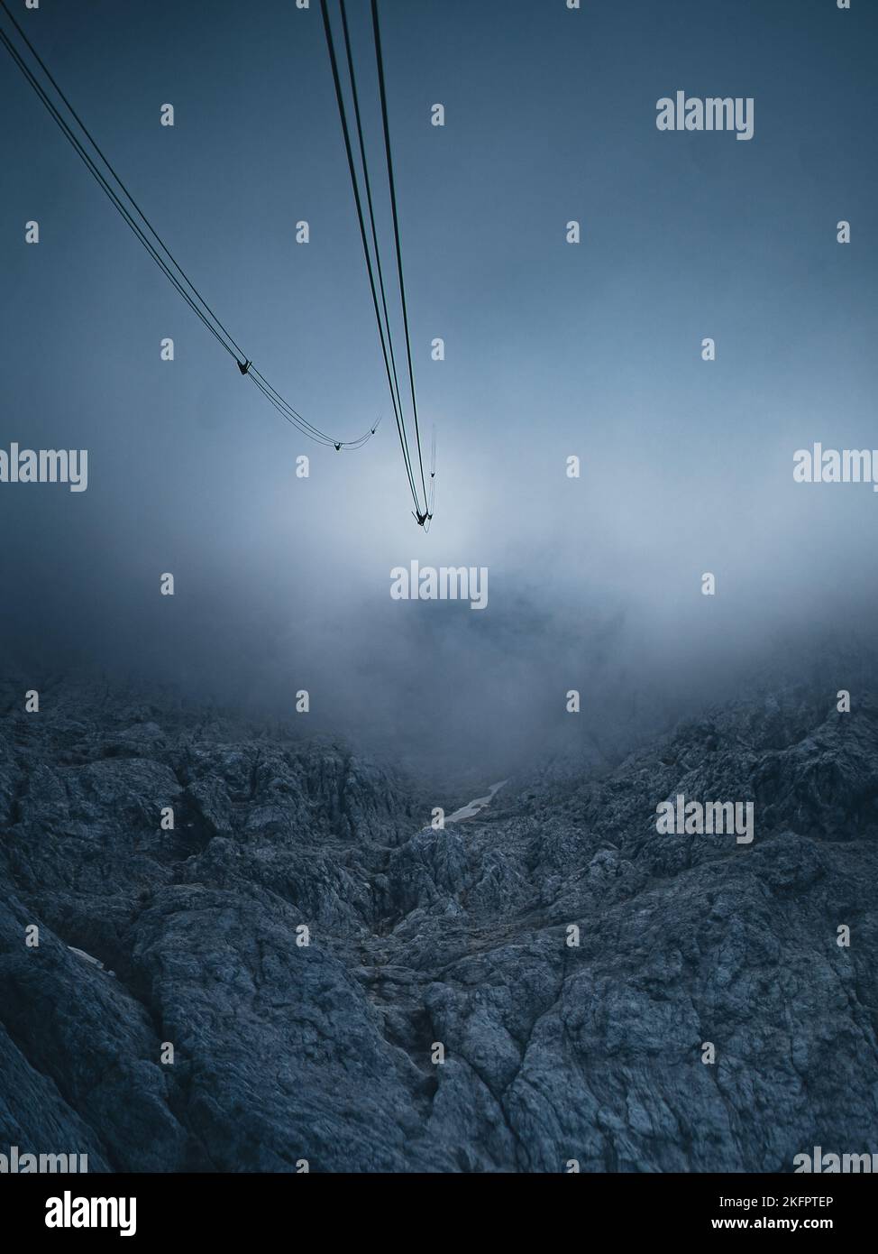 A beautiful view of cable wires over a rocky landscape on a cloudy day ...