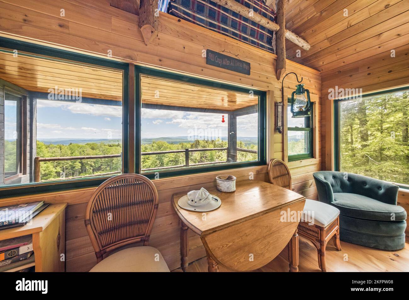 A rustic room with a view of greenery and blue sky from big windows and ...