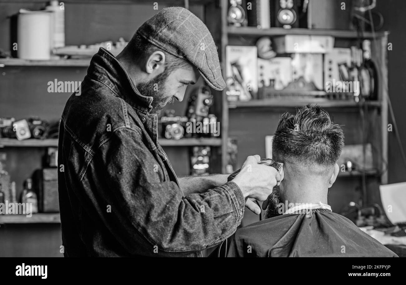 Barber with clipper trimming hair of client, rear view. Barber with ...
