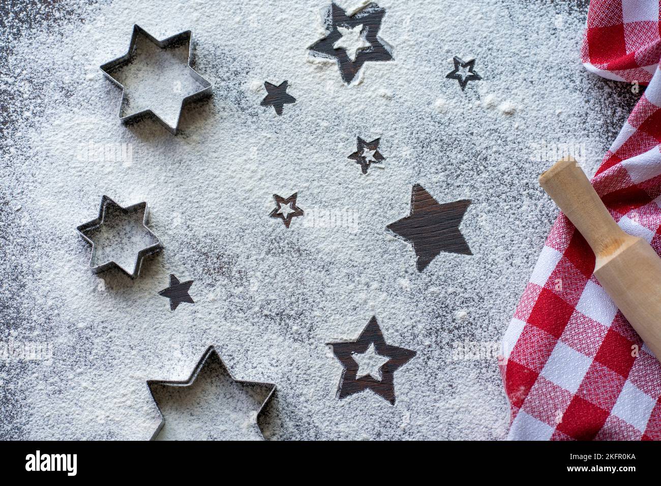 dark wooden table with flour and red chequered tablecloth, rolling pin ...