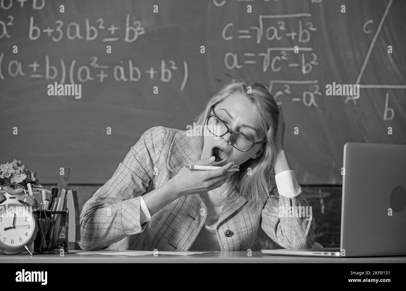 Work far beyond actual school day. Teacher woman sit table classroom ...