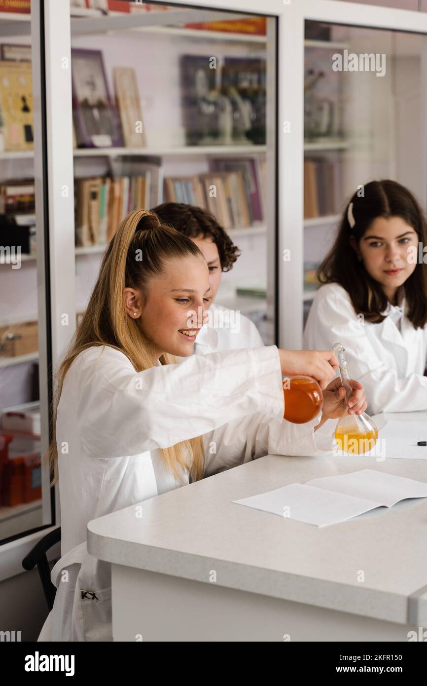 School education. Cheerful classmates in chemistry lesson hold flasks ...