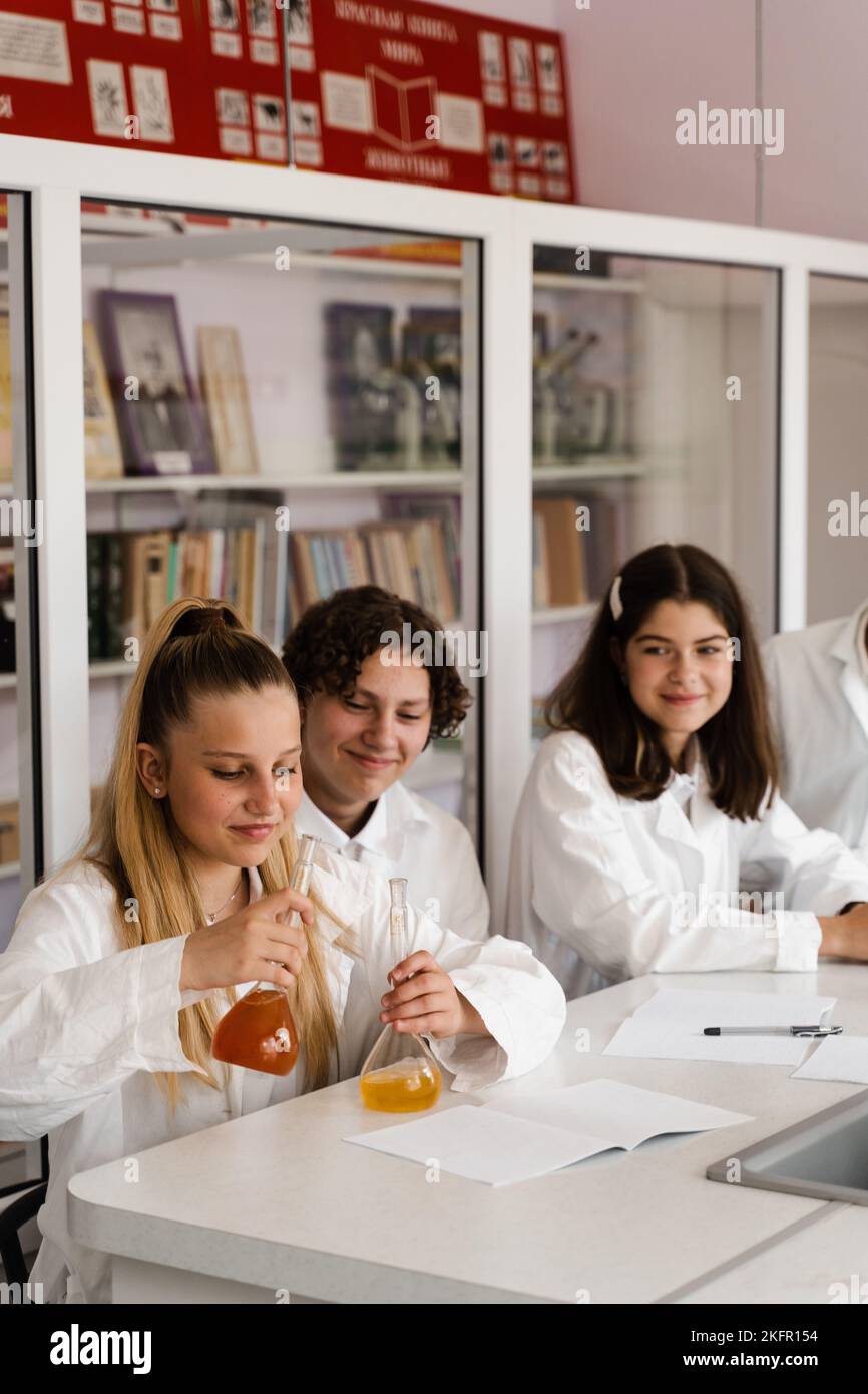 School education. Cheerful classmates in chemistry lesson hold flasks ...