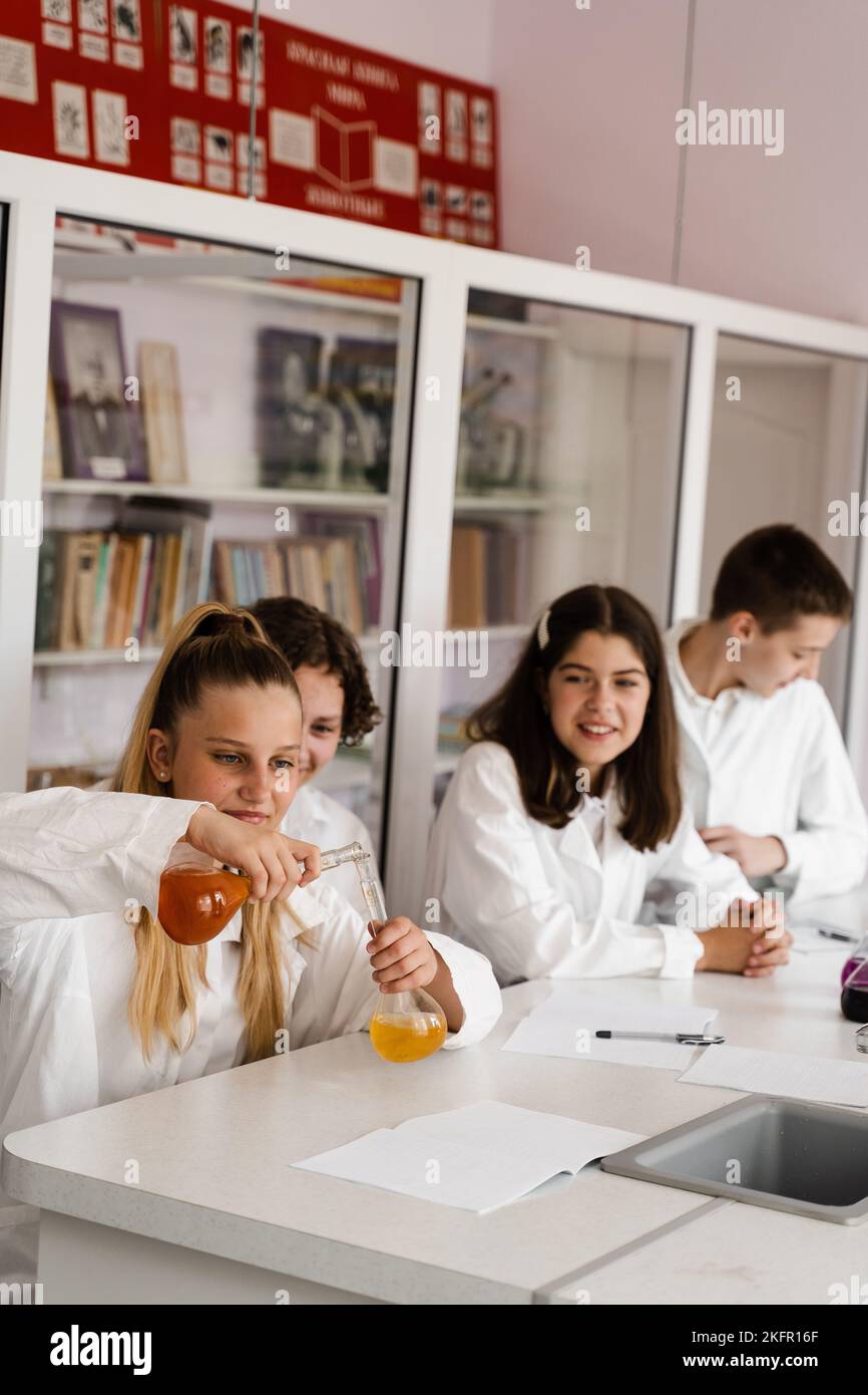 School education. Cheerful classmates in chemistry lesson hold flasks ...