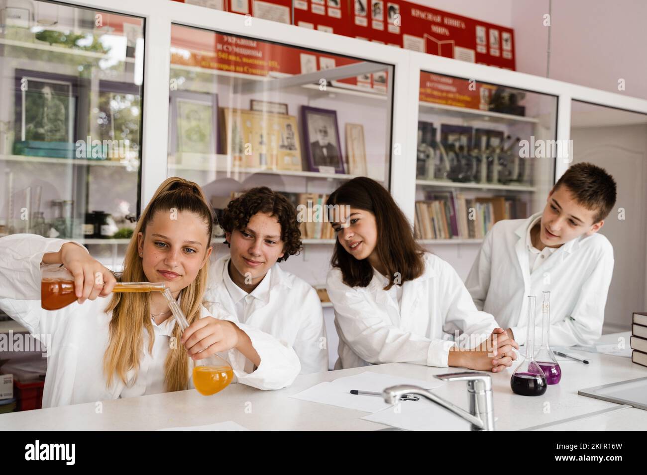 Chemistry lesson. Schoolgirl and classmates holds flask for experiments ...