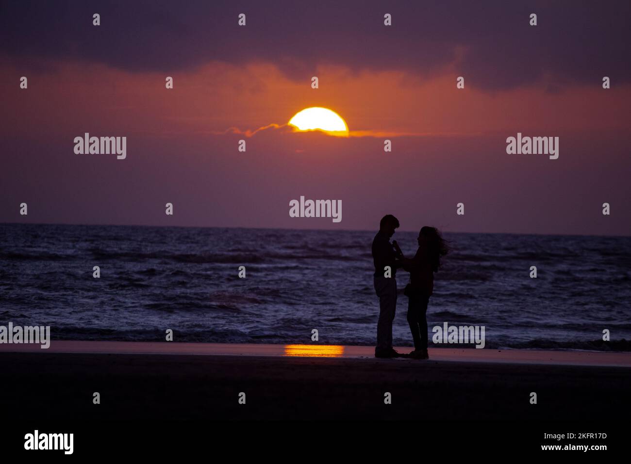A silhouette of a lovely couple together on Amalfi beach at sunset in ...