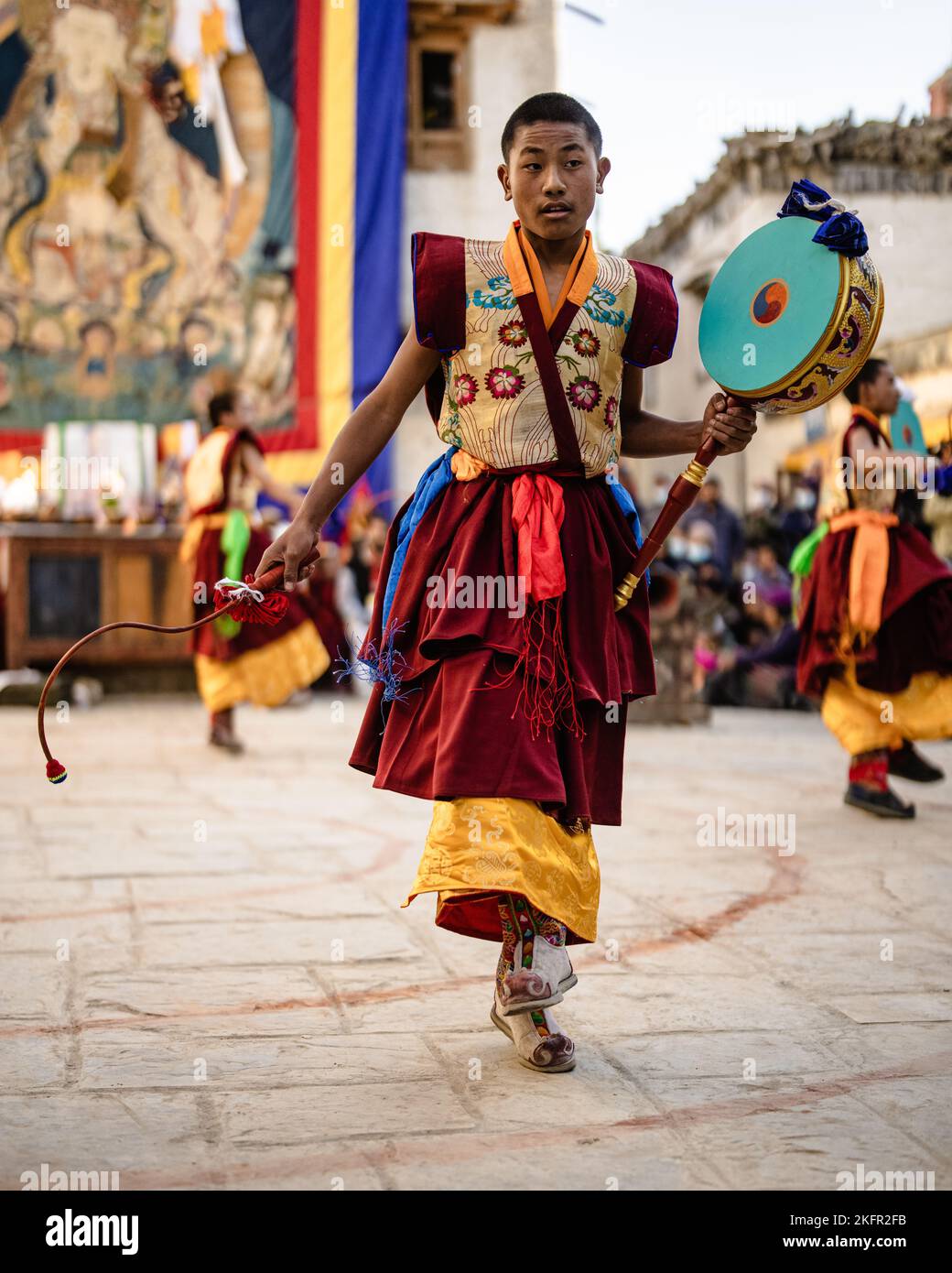 A young Tibetan Buddhist in traditional outfit Dancing holding a Damaru ...