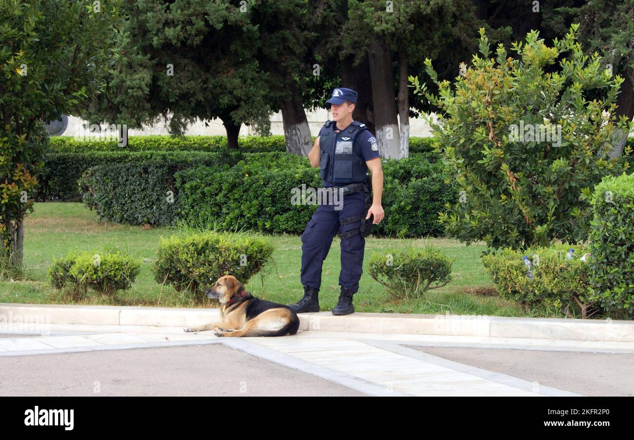 Police officer in dark blue uniform standing in the park, with a brown ...