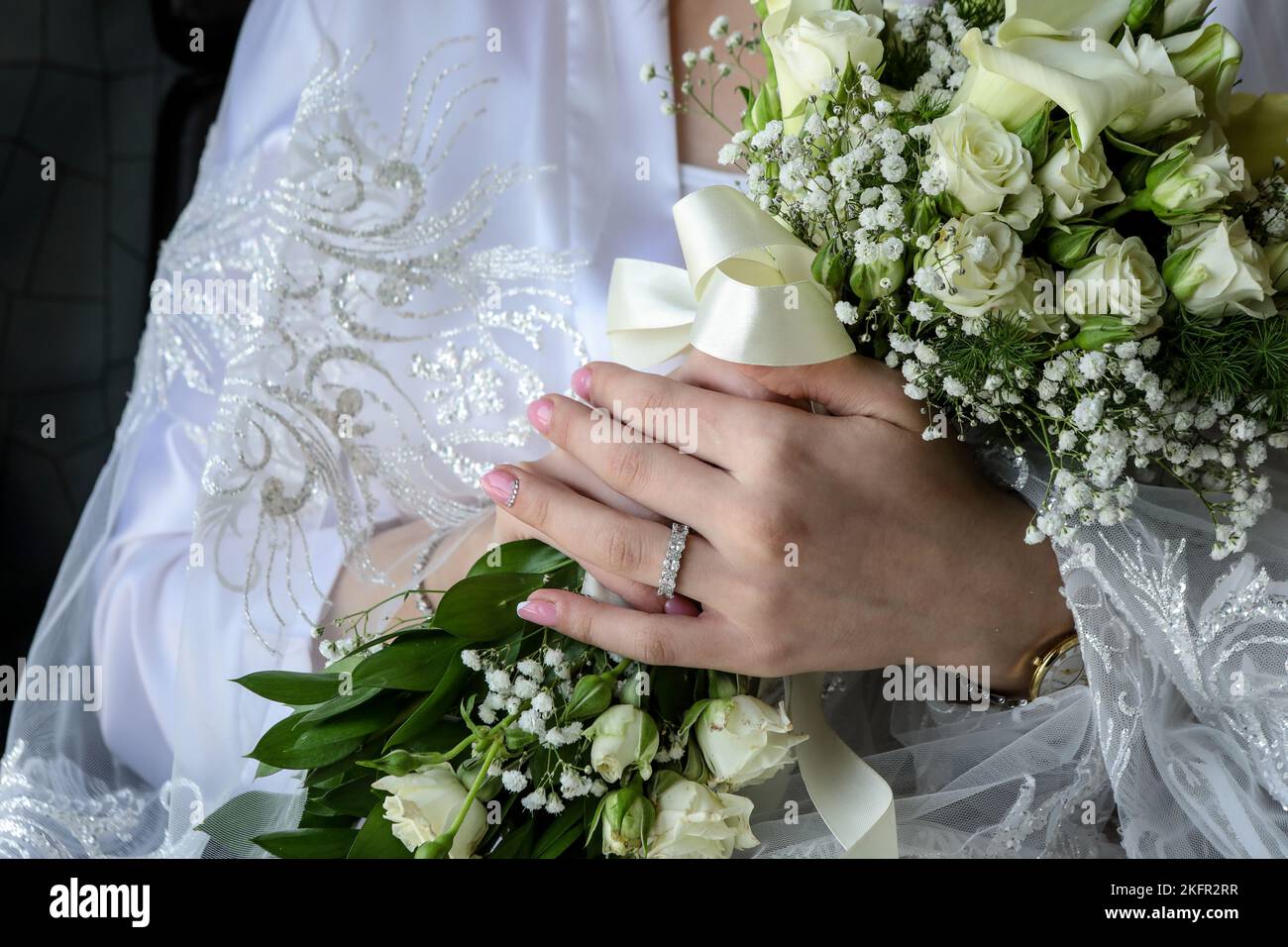 A closeup shot of a bride holding a white green bouquet with a hand ...