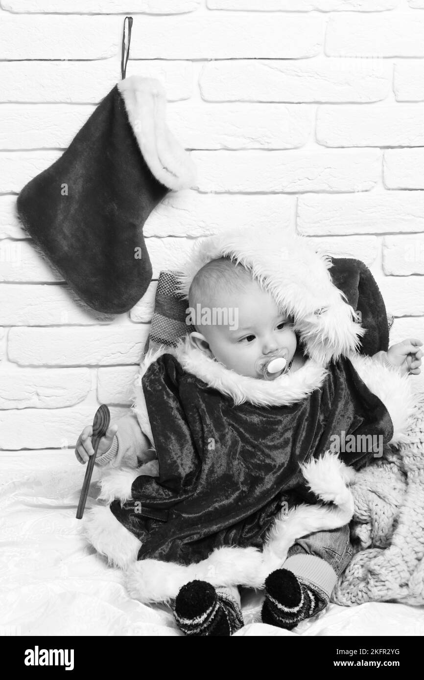 small baby boy with adorable curious face in red sweater with dummy in ...