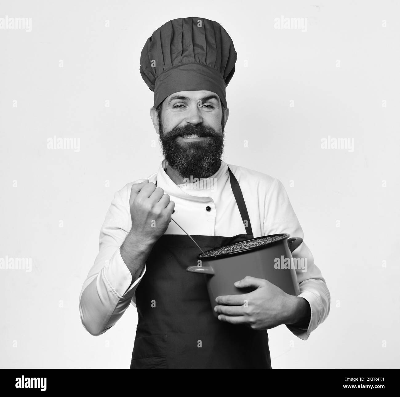 Cook with smile in burgundy uniform has casserole with ladle Stock ...