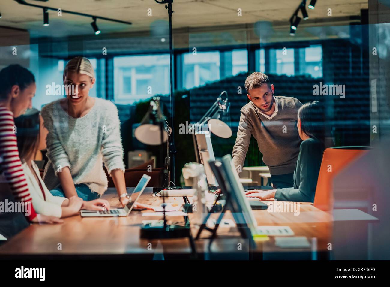 Three young women in a modern office solve a problem together while ...