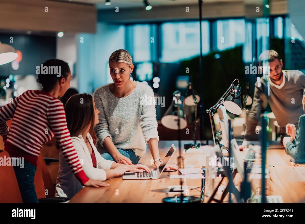 Three young women in a modern office solve a problem together while ...