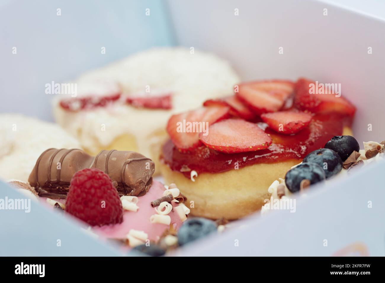 A box of tasty donuts topped with cream, chocolates, and blackberries ...