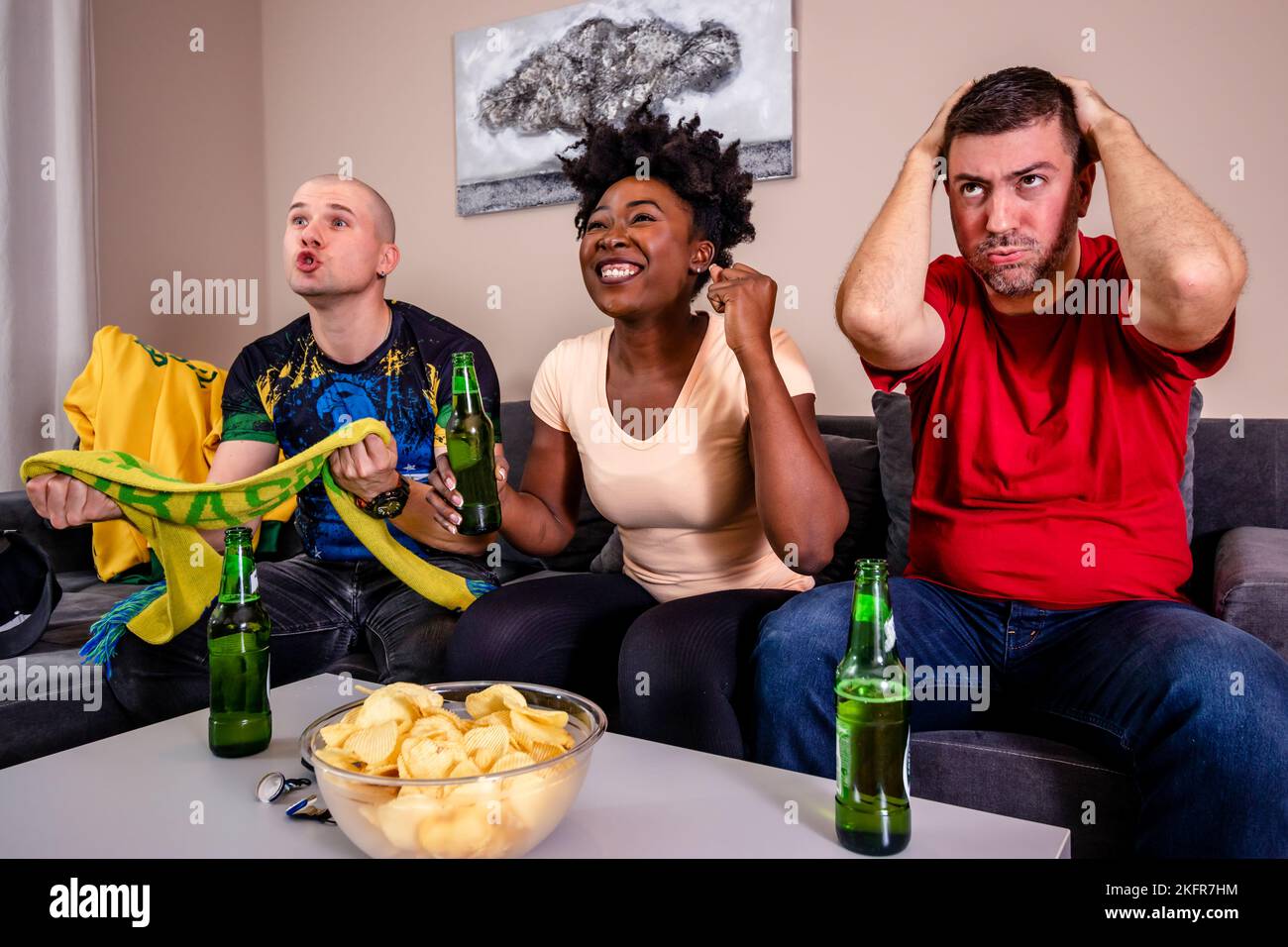 Friends watching a football match on TV, drinking beer and eating chips ...