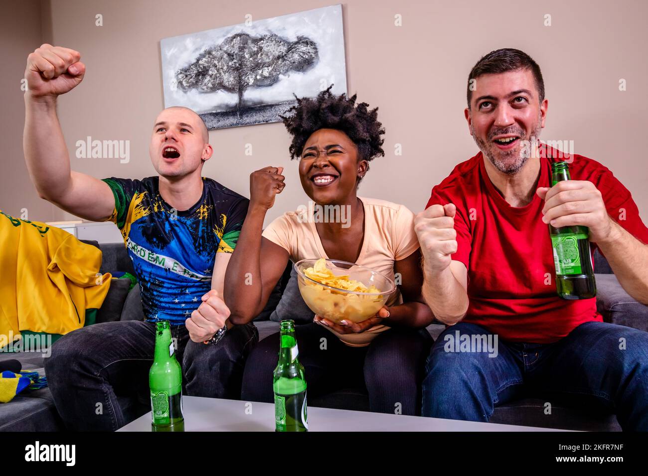 Friends watching a football match on TV, drinking beer and eating chips ...