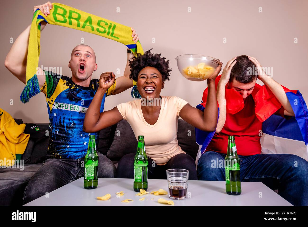 Friends watching a football match on TV, cheering for their national ...